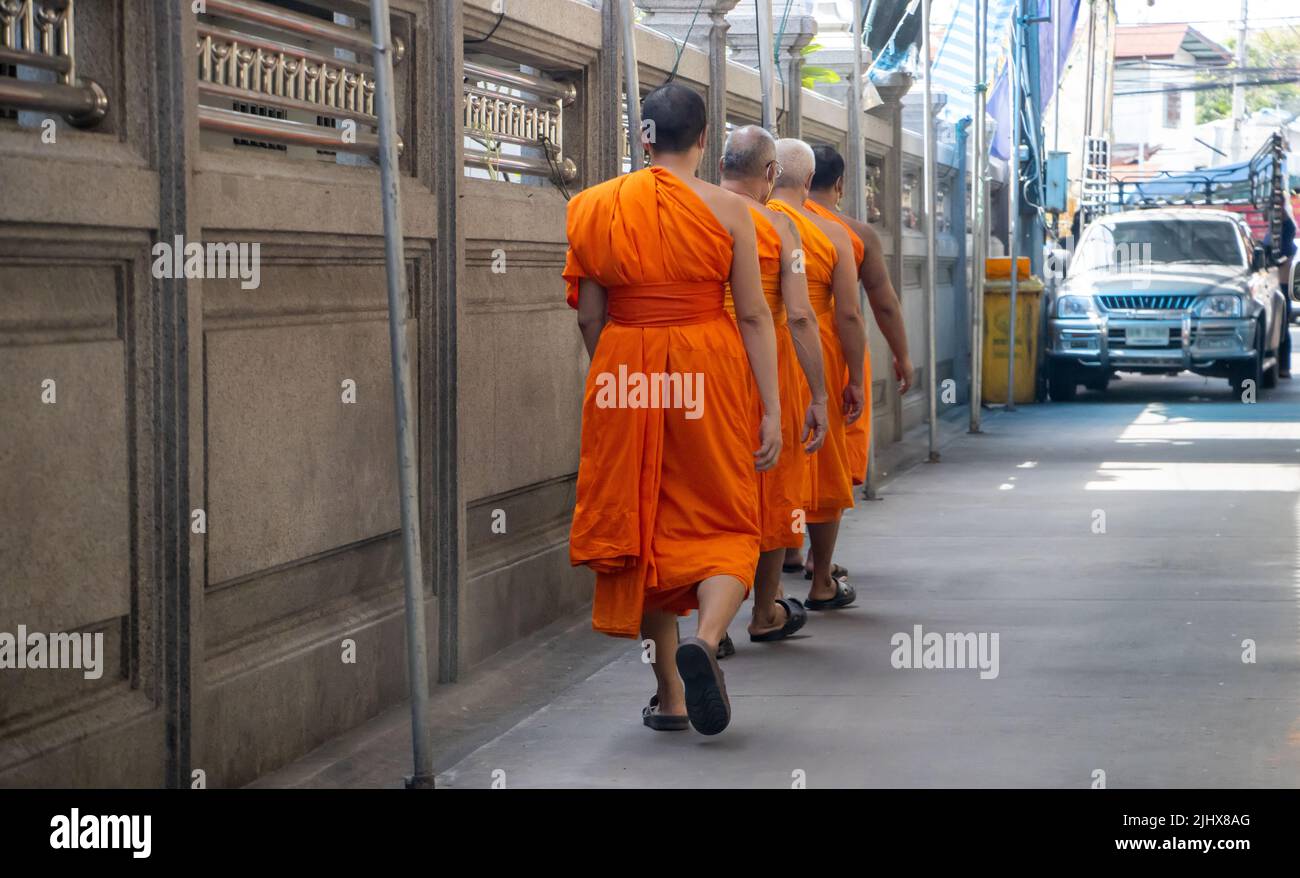 Group of monks walking in single line on the street, rear view ...