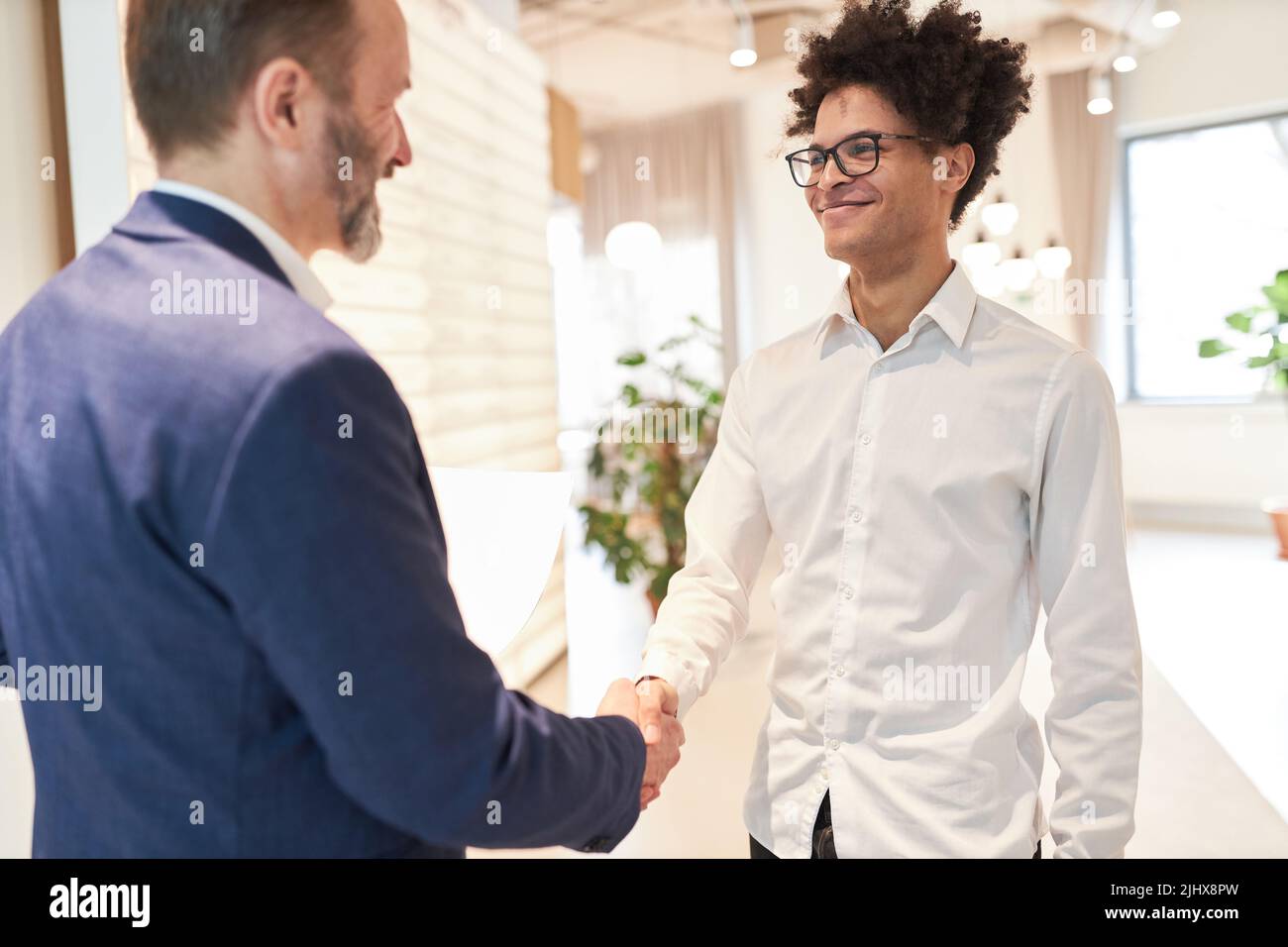 Business man and young startup founder shaking hands as a greeting or ...