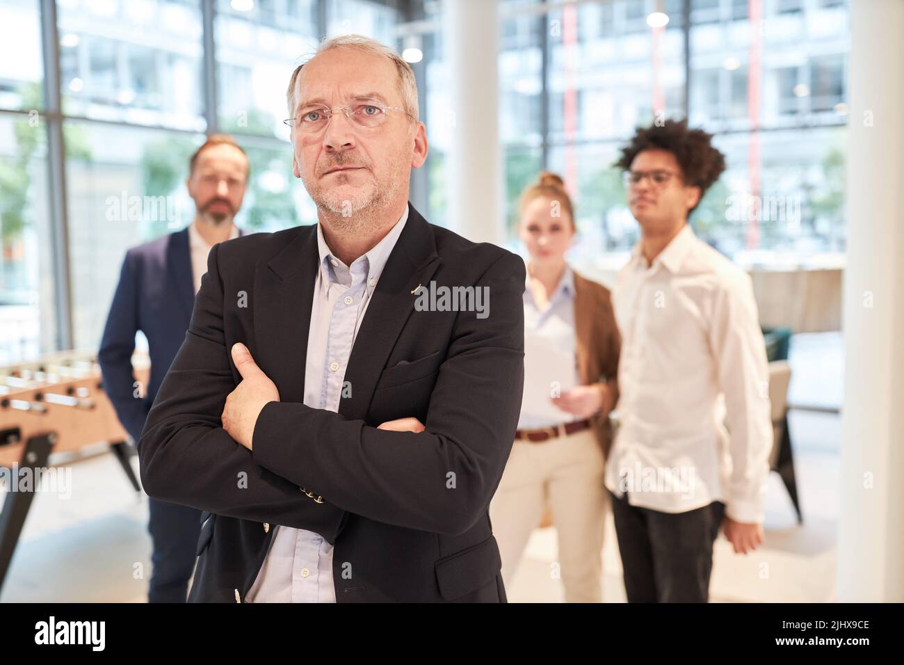 Senior business man as a confident manager or boss in front of his team ...