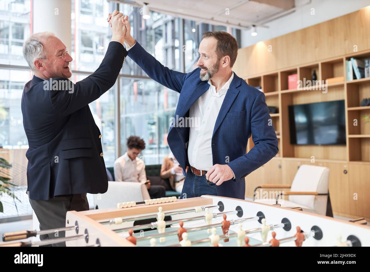 Business people play foosball at the foosball table in the office and ...