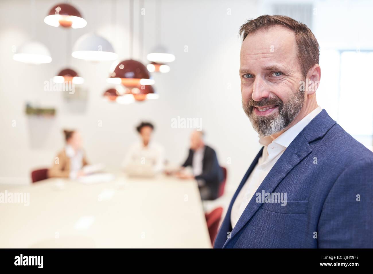 Confident businessman as a successful startup founder with team in the ...