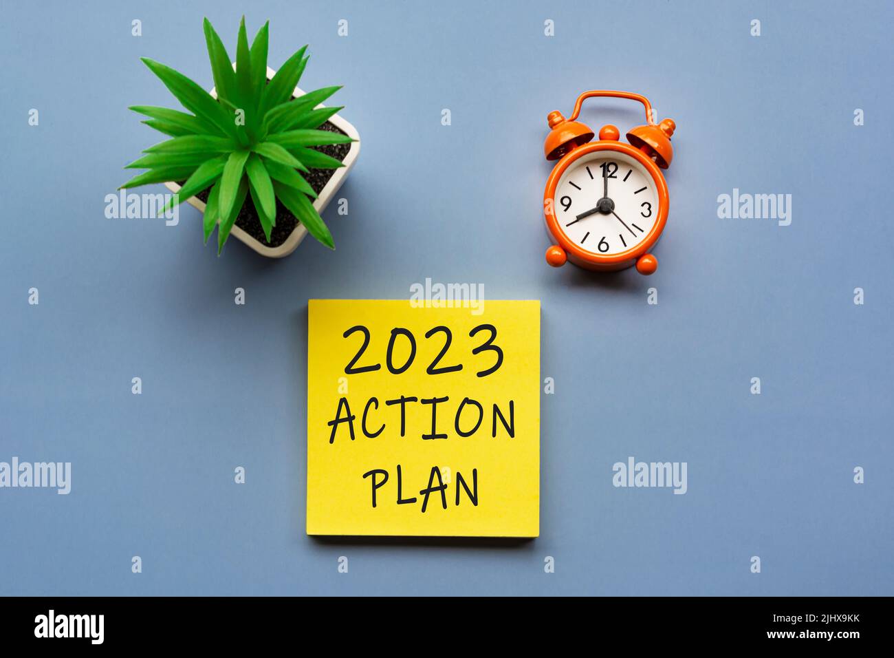 2023 action plan written on Adhesive Note and alarm clock set at 8 o ...