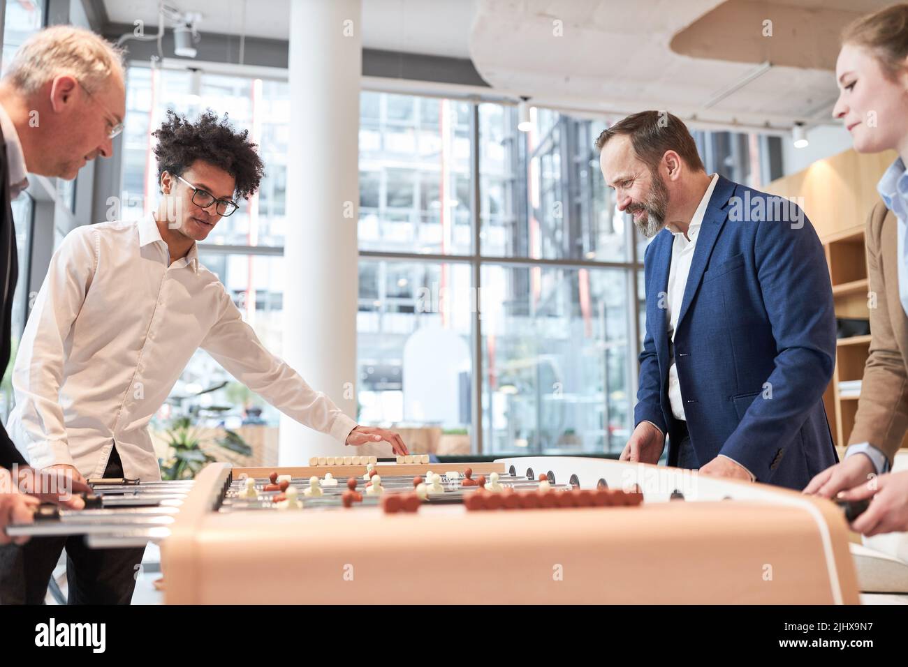 Business people playing table football at the foosball table to relax ...