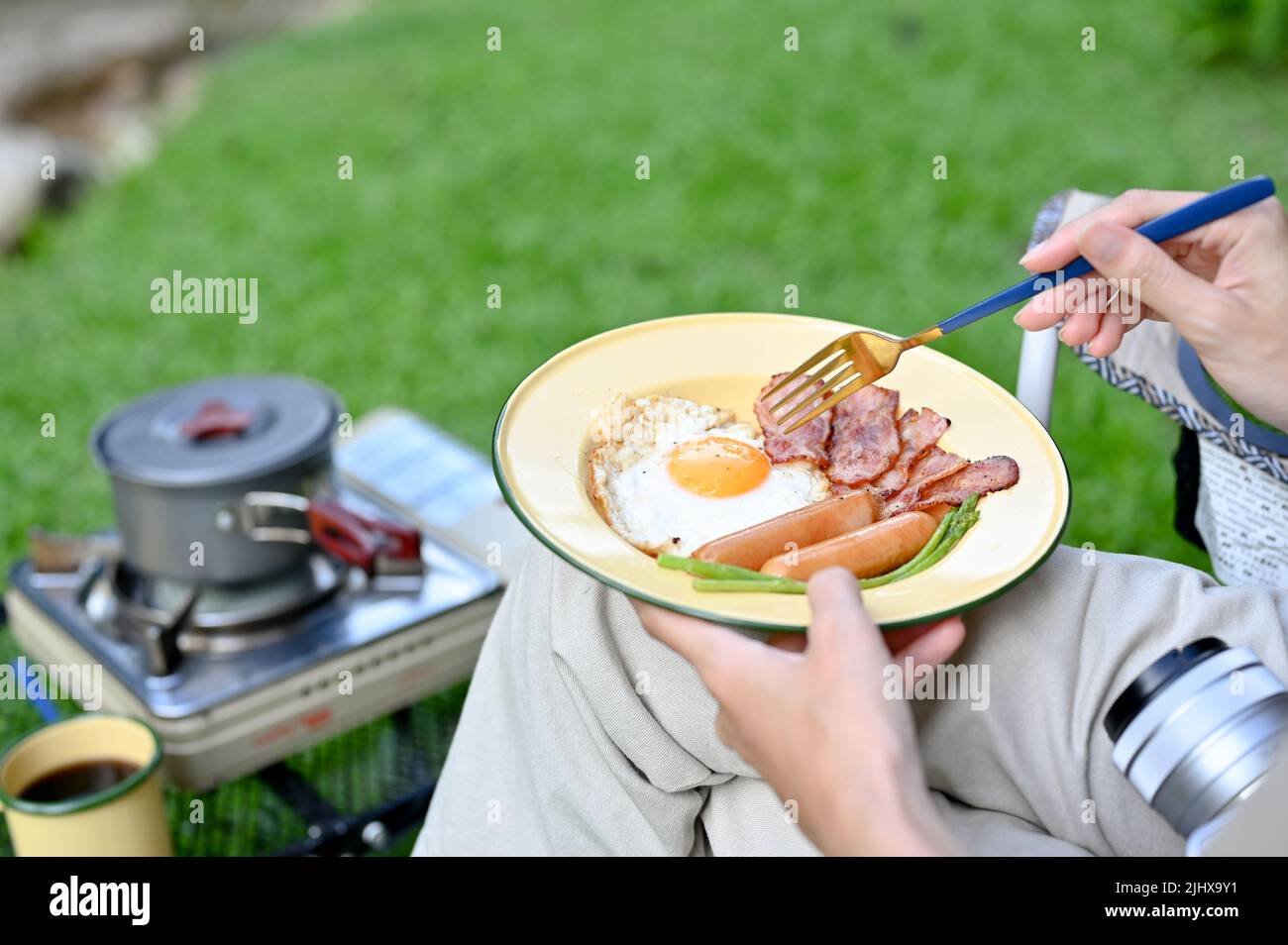 Female camper traveler eating her breakfast while enjoy camping at the ...