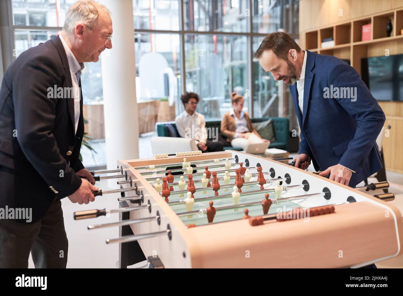 Two business people as colleagues play table football at the foosball ...