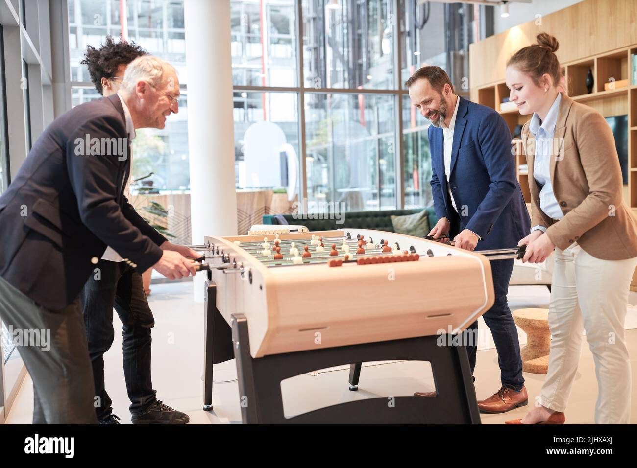 Group of business people playing table football at the foosball table ...