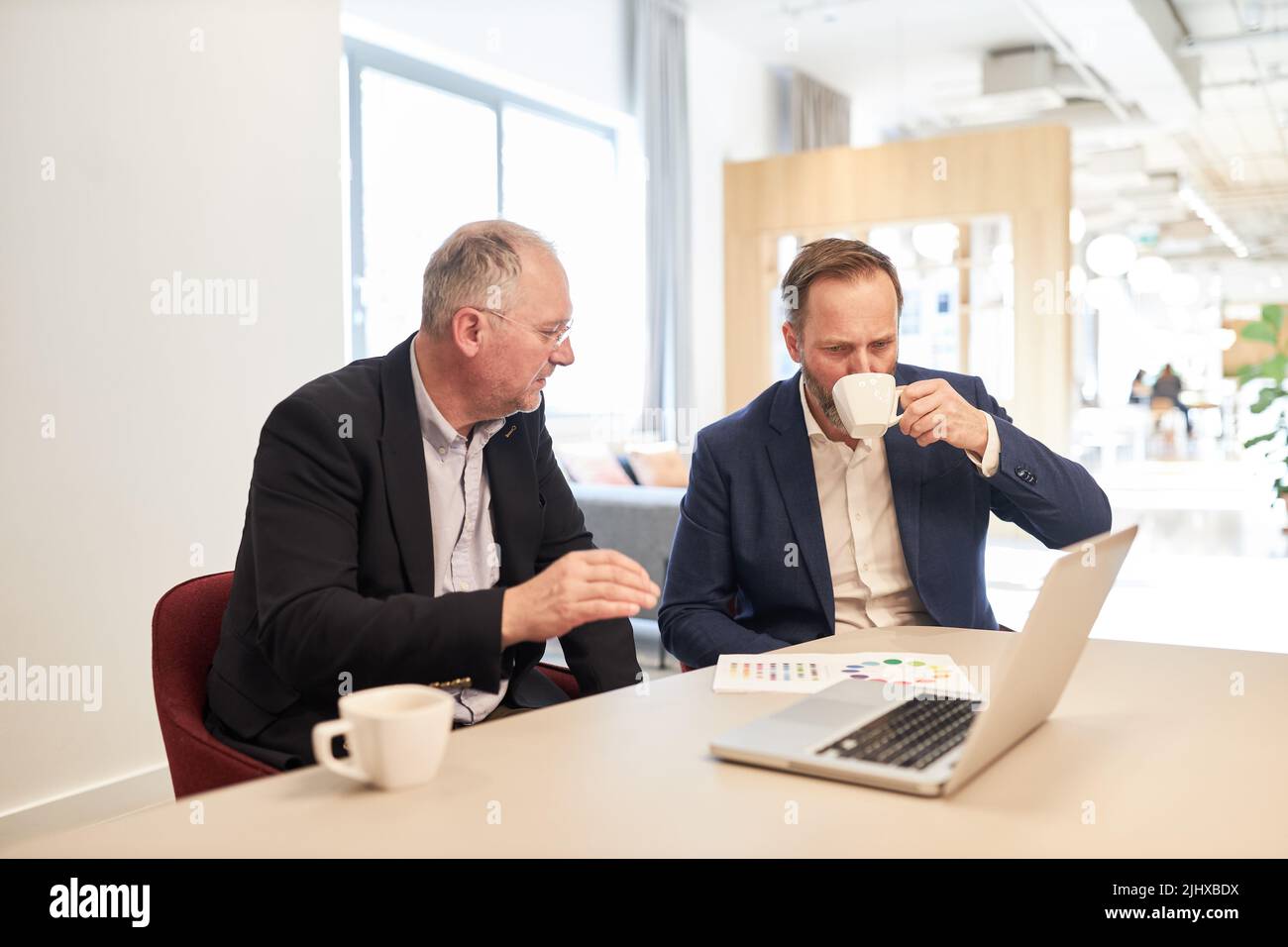 Two business people are taking coffee break in the office with laptop ...