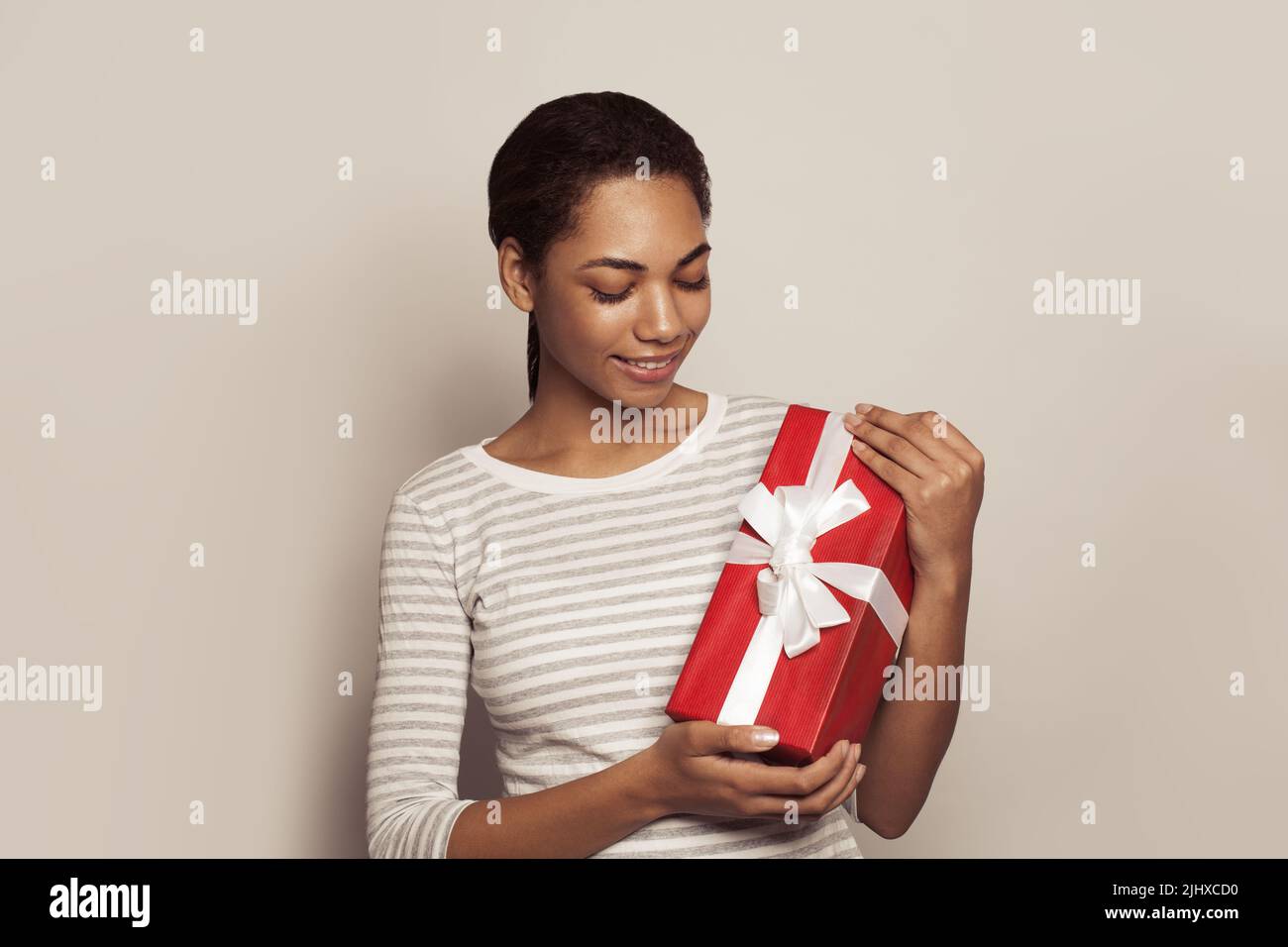 Happy young African American woman with red gift present box in her ...