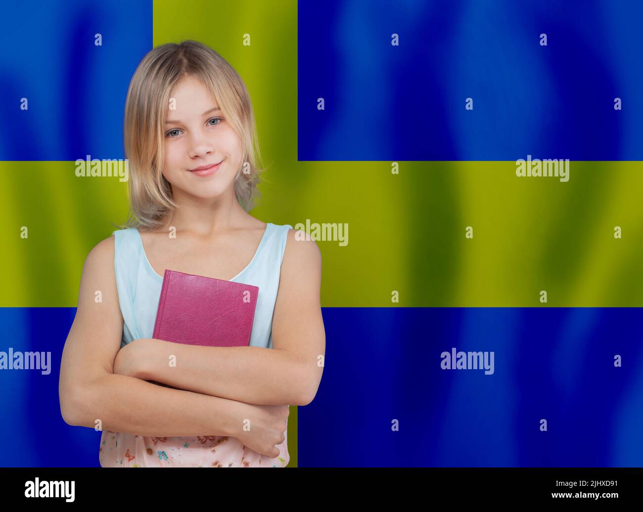 Young happy child girl with blonde hair holding book against Swedish ...