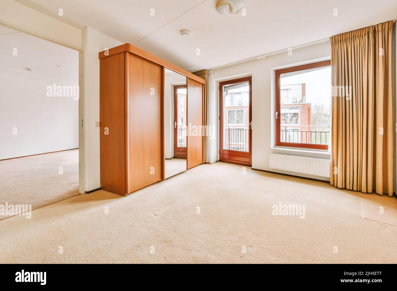 Wardrobe with window placed near doors in spacious room with white ...