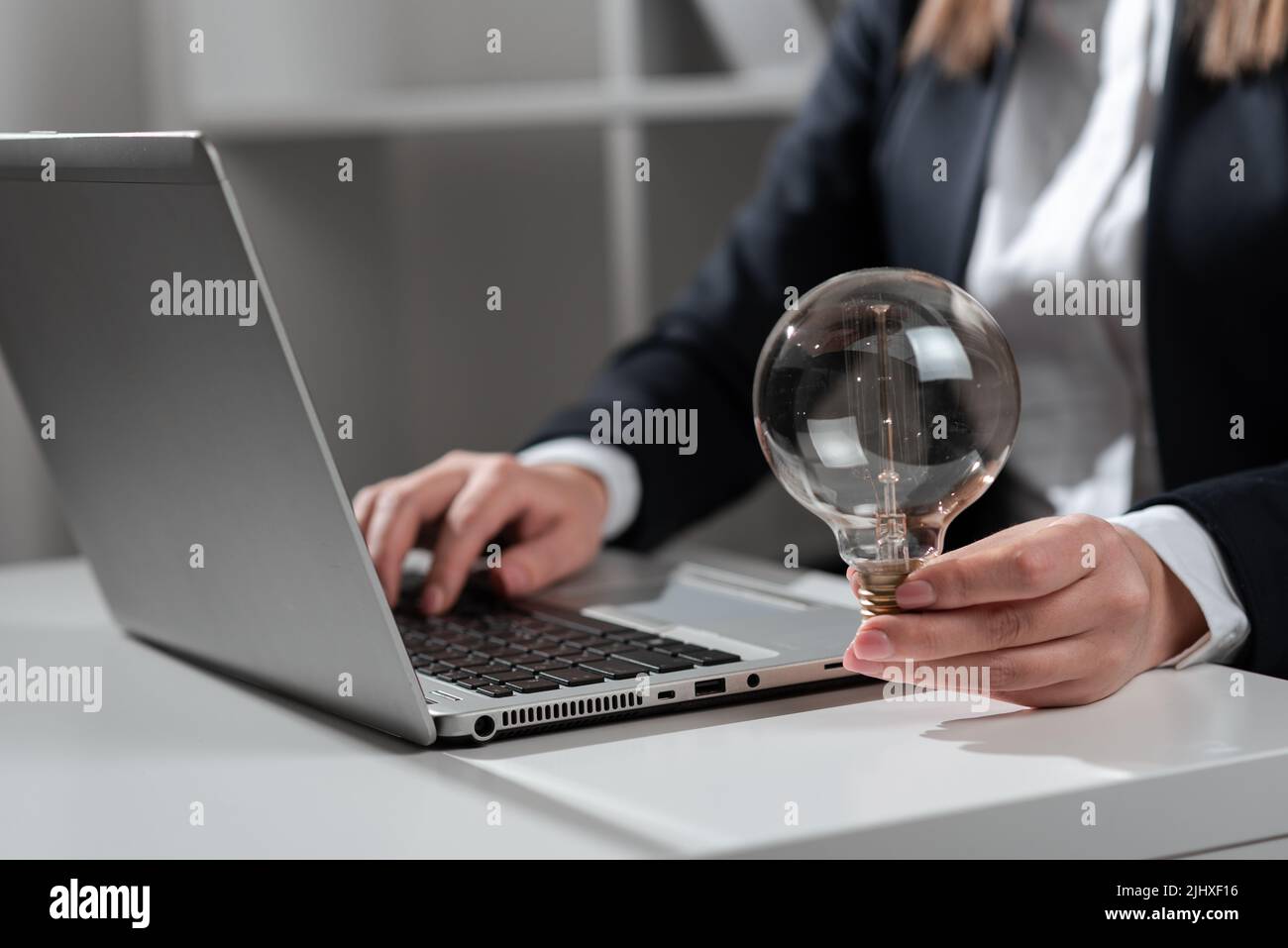Businesswoman Typing Recent Updates On Lap Top On Desk Holding ...
