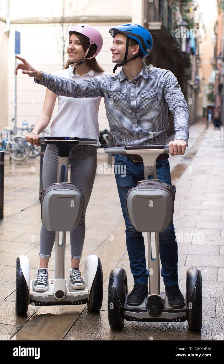 young couple guy and girl walking on segway in streets of european city ...