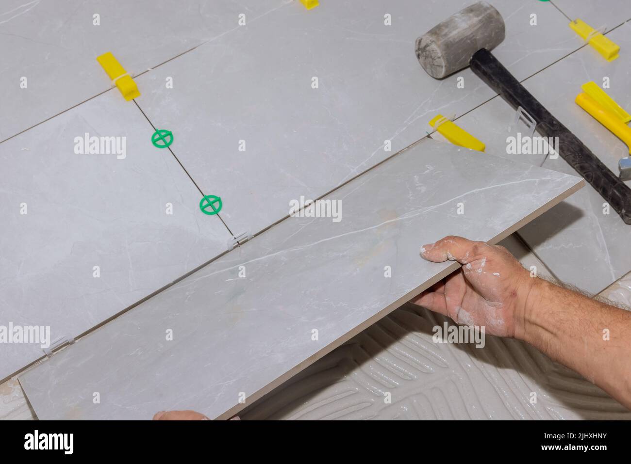 Placing ceramic floor tiles on adhesive surface with home construction ...