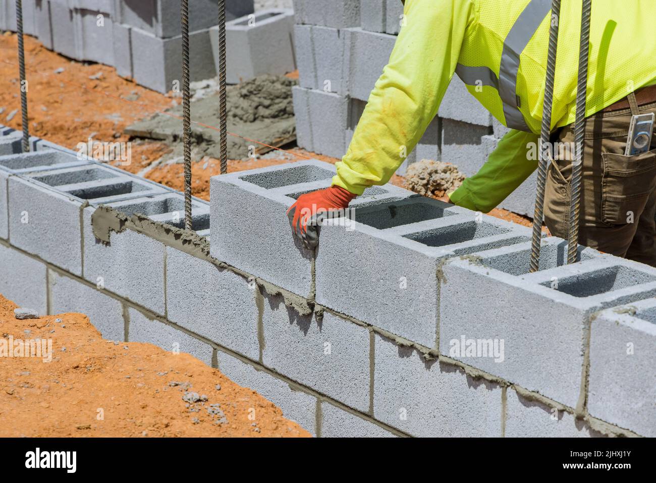 A mason is in the process of mounting a wall of aerated concrete blocks ...