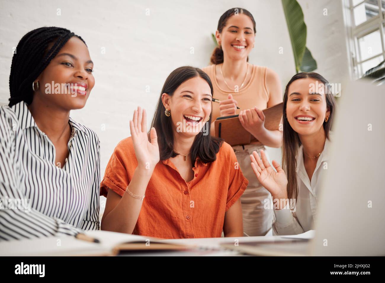 Diverse group of business women waving hello to colleagues during a ...