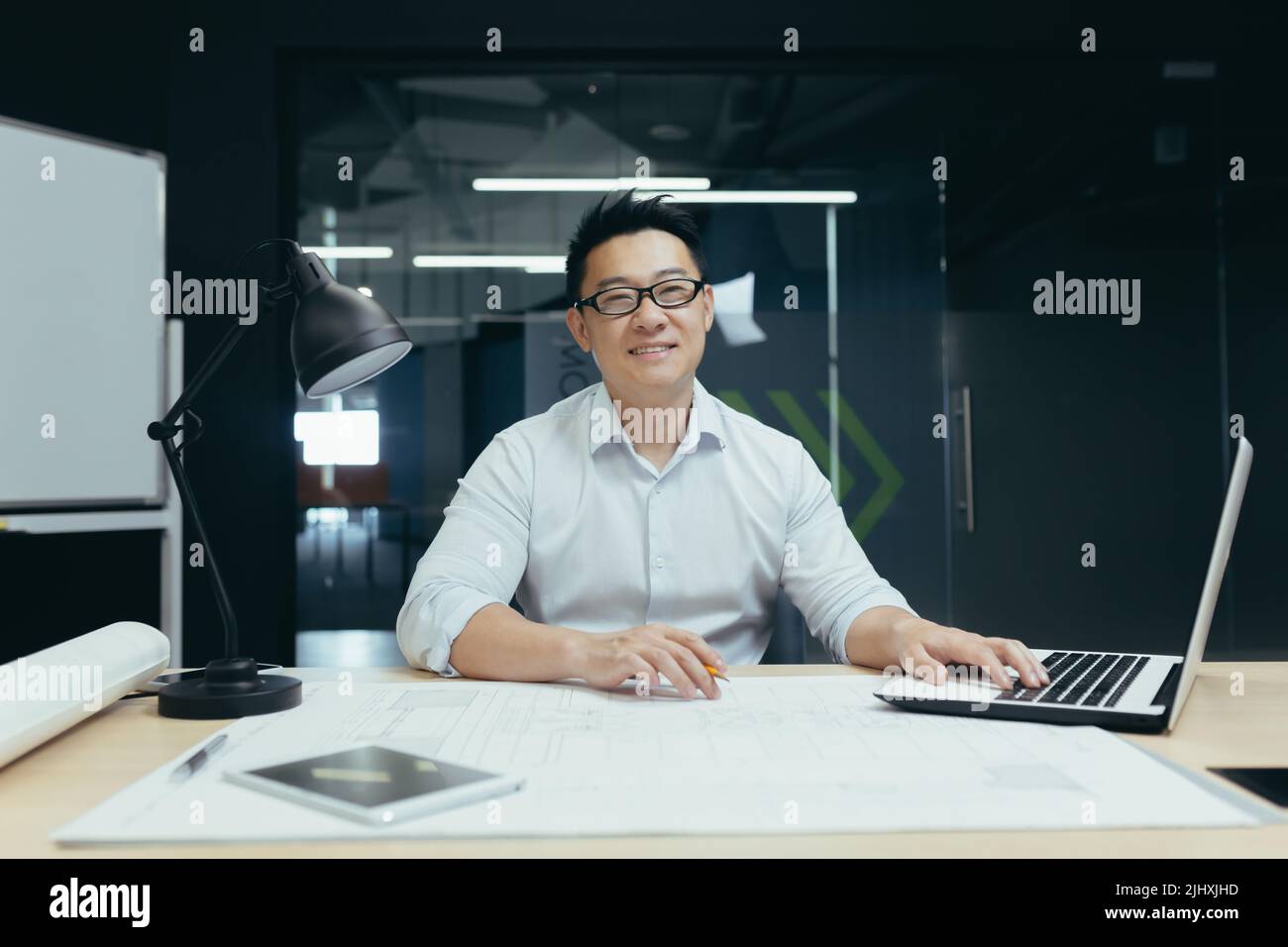 Portrait of successful asian male architect smiling and looking at ...