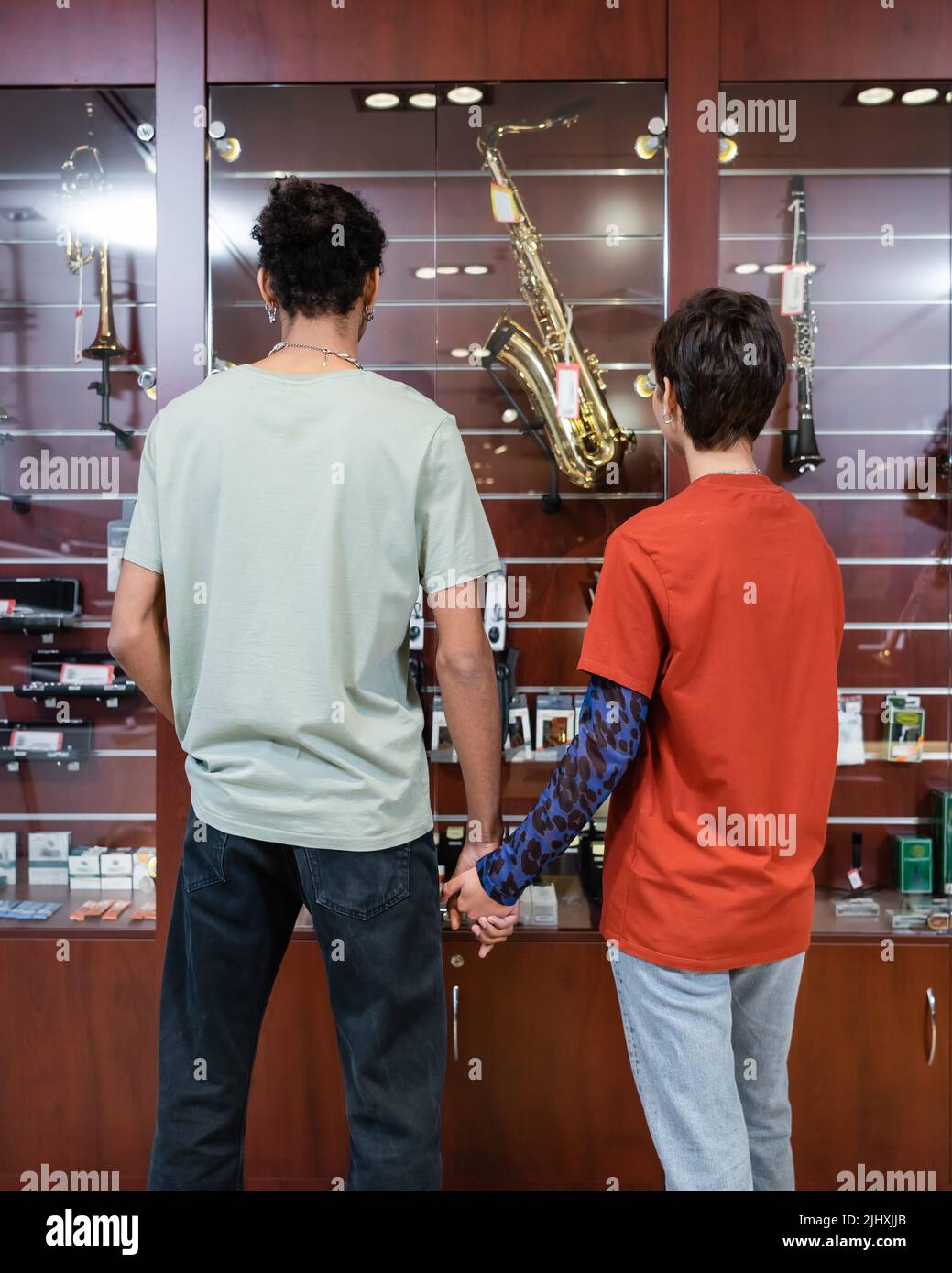 Back view of interracial couple choosing musical instrument in shop ...