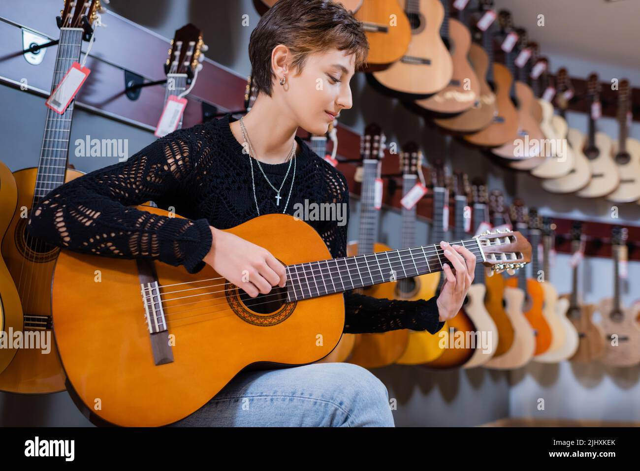 Side view of customer playing acoustic guitar in instrumental music ...