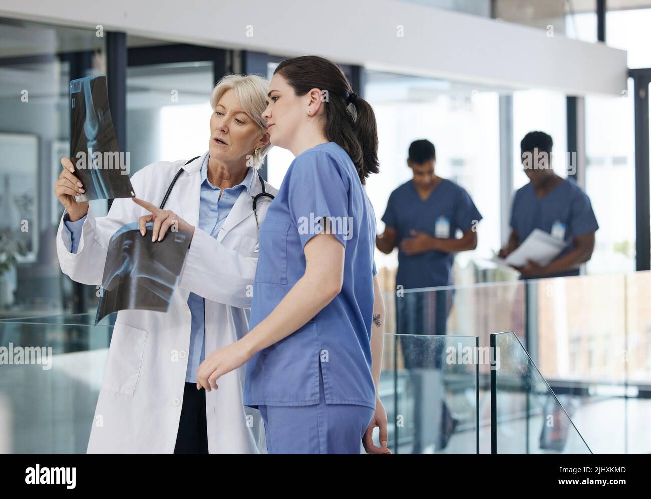 Solving problems together. two female doctors examining an x-ray at a ...