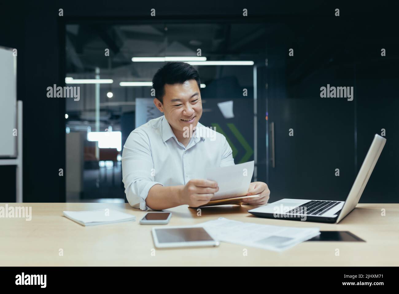 Happy and successful asian businessman reading financial document ...