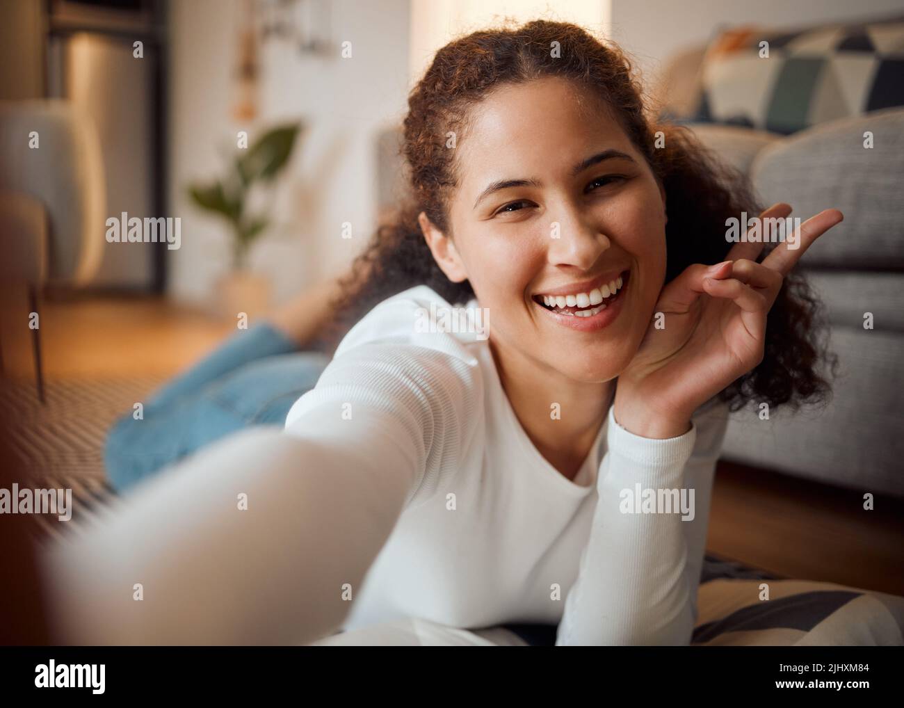 Cheerful woman taking a selfie at home. Young woman making the peace ...