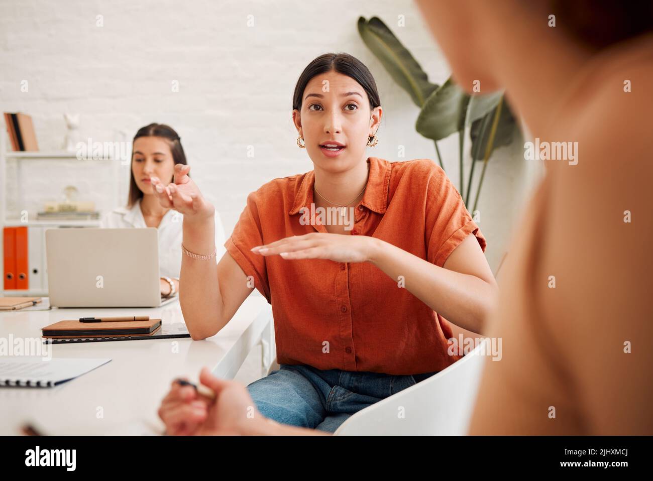 Young hispanic business woman speaking to colleagues during a meeting ...