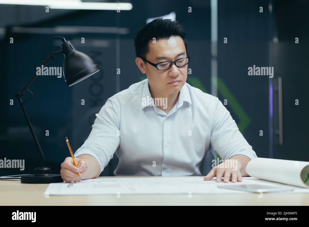 Asian designer working on blueprint in modern office, male architect ...