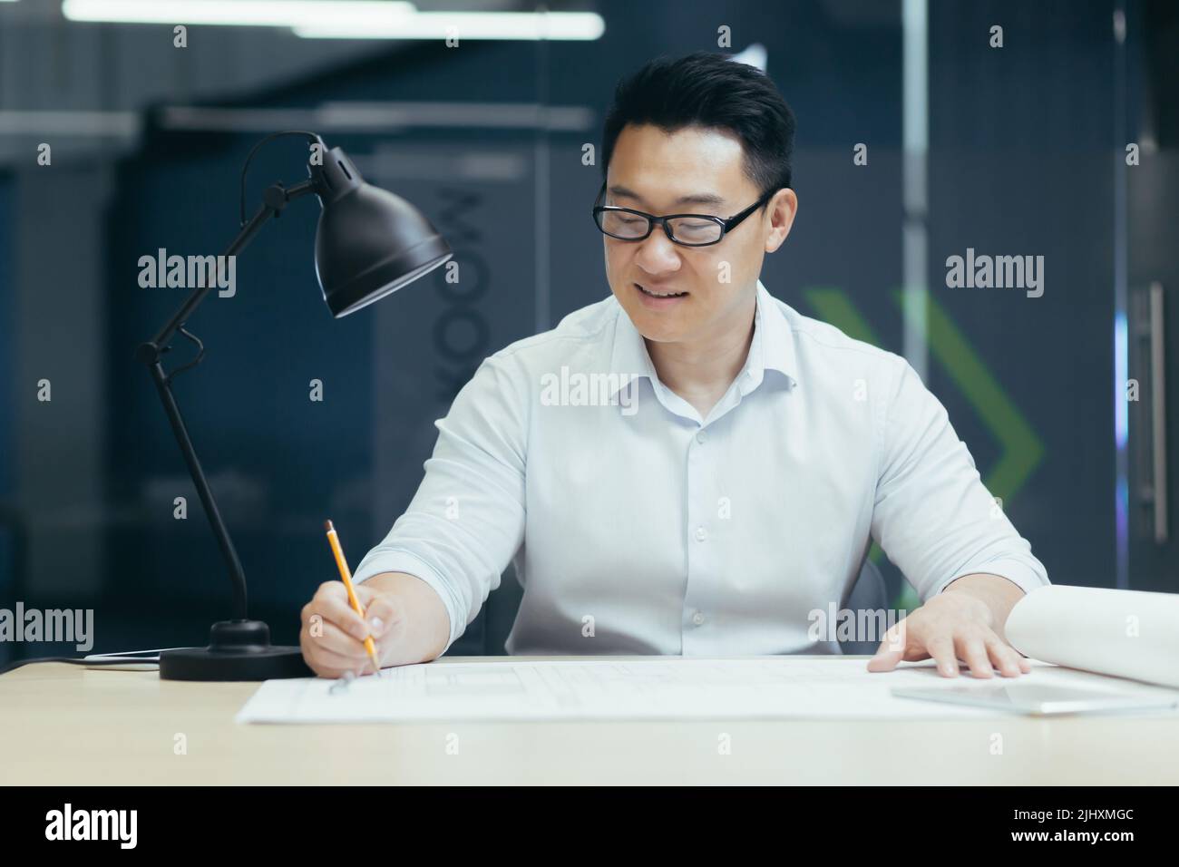 Successful Asian architect works in design studio, on plan drawing of ...