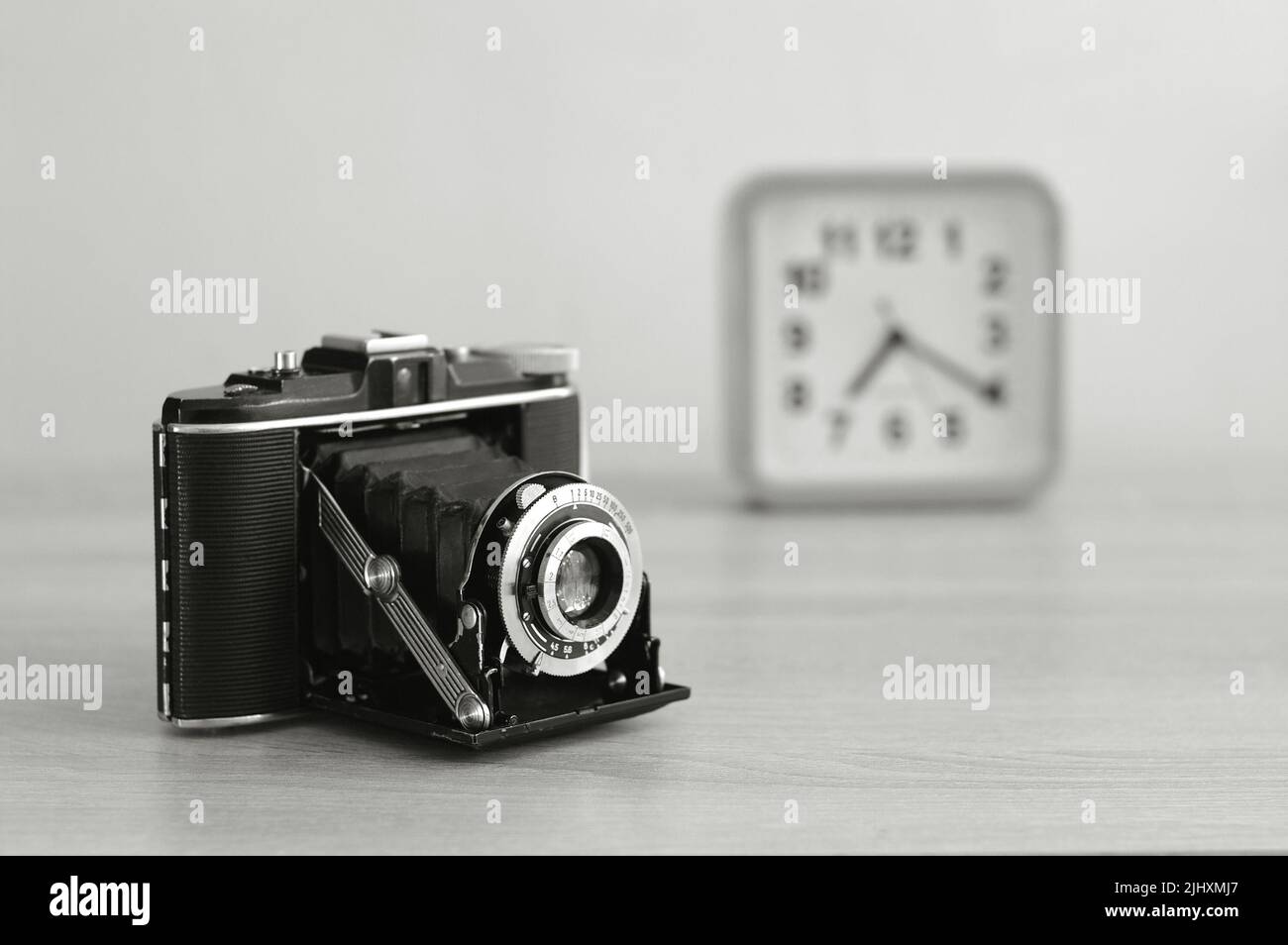 Vintage analog medium format film camera and a clock in black and white ...