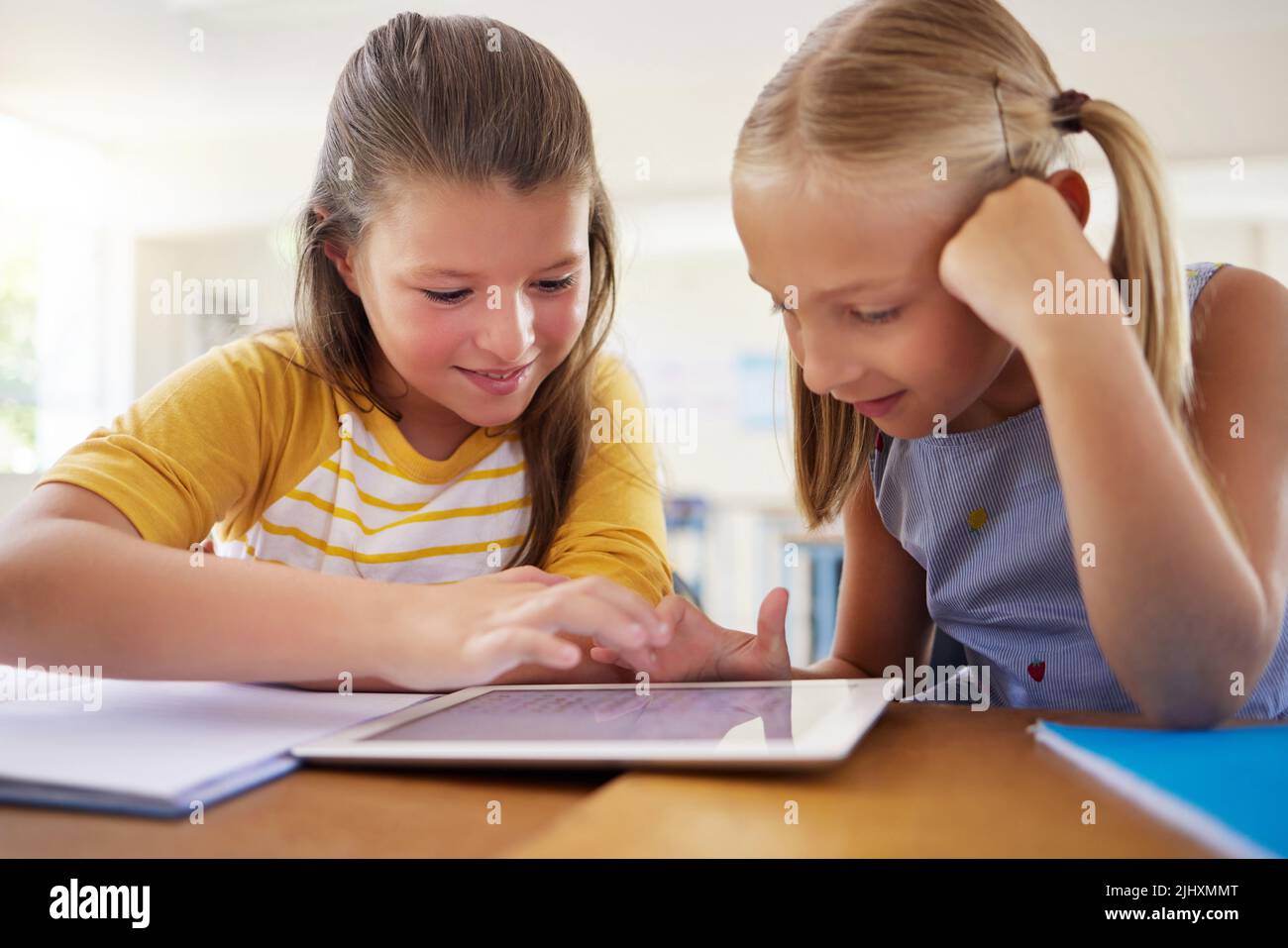 This is my new friend. two girls using a tablet in a classroom Stock ...