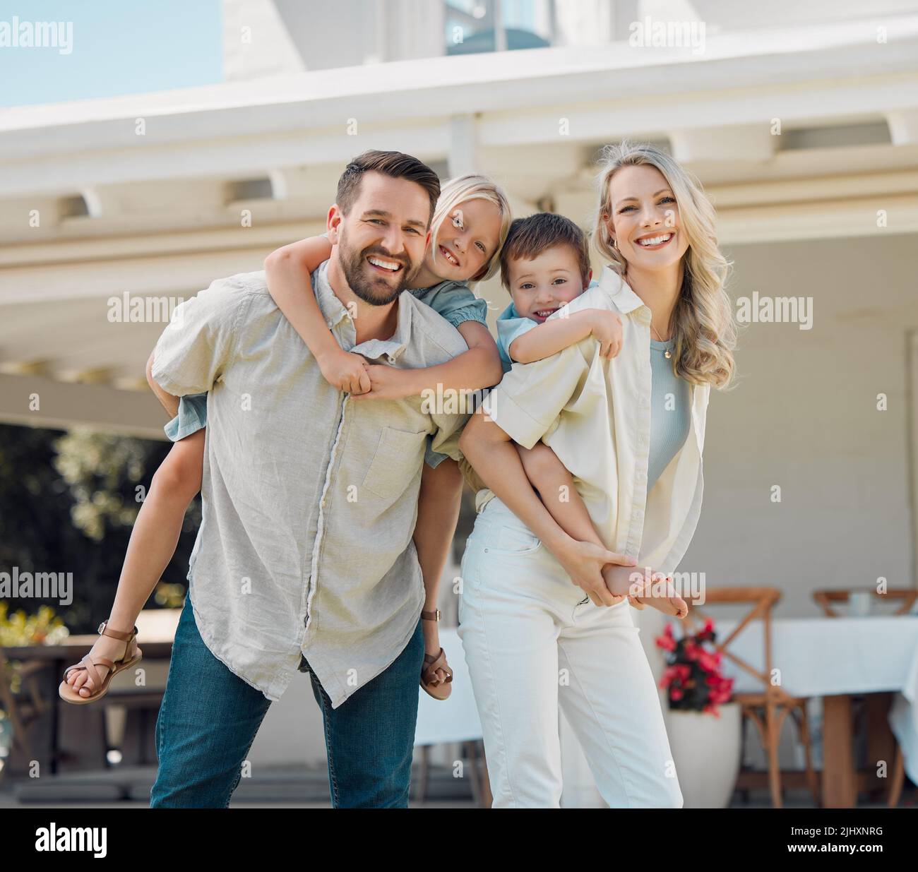 Portrait of happy parents giving their little children piggyback rides ...