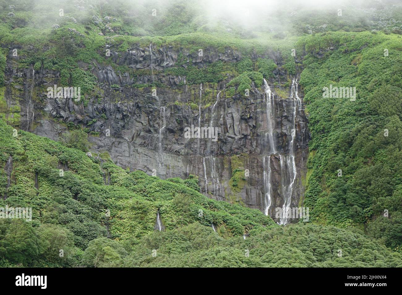 An aerial view of greenery hills with flowing waterfalls falling from ...