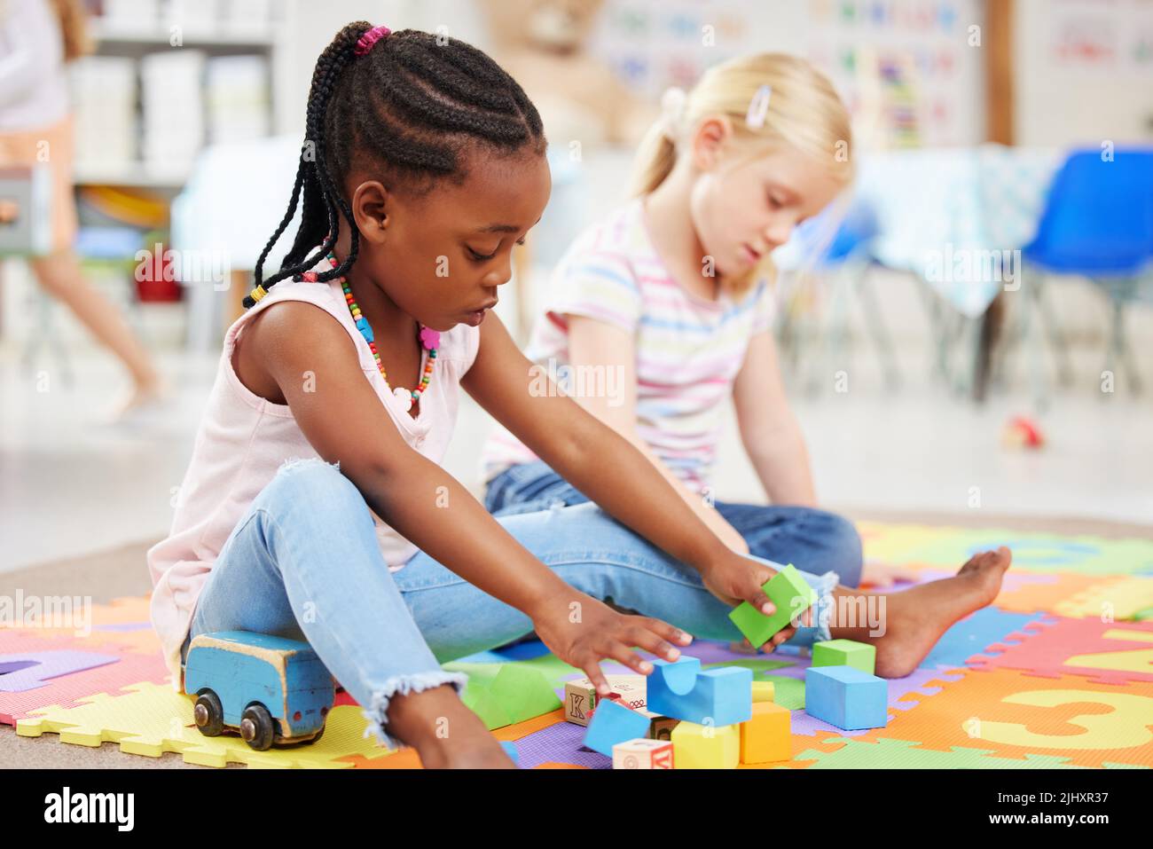 Little african american girl and classmate playing with colourful ...