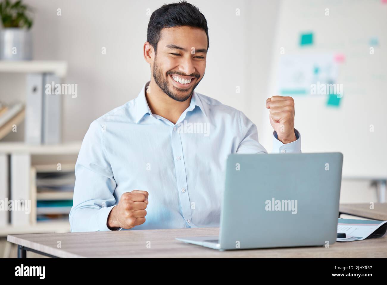 Young happy and excited mixed race businessman cheering with his fist ... Young happy and excited mixed race businessman cheering with his fist ...
