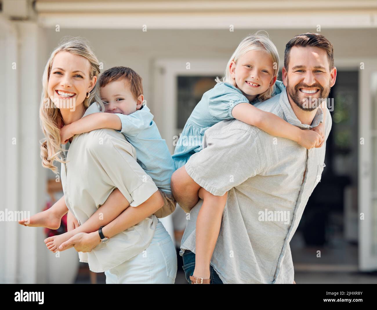 Portrait of happy parents giving their little children piggyback rides ...