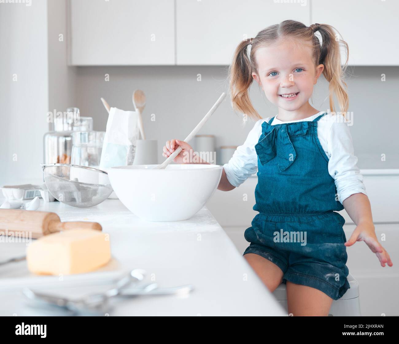 Happy little girl baking alone. Caucasian child baking in her kitchen ...