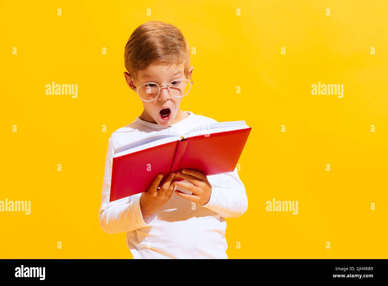 Portrait of cute little boy, happy kid reading book isolated on bright ...