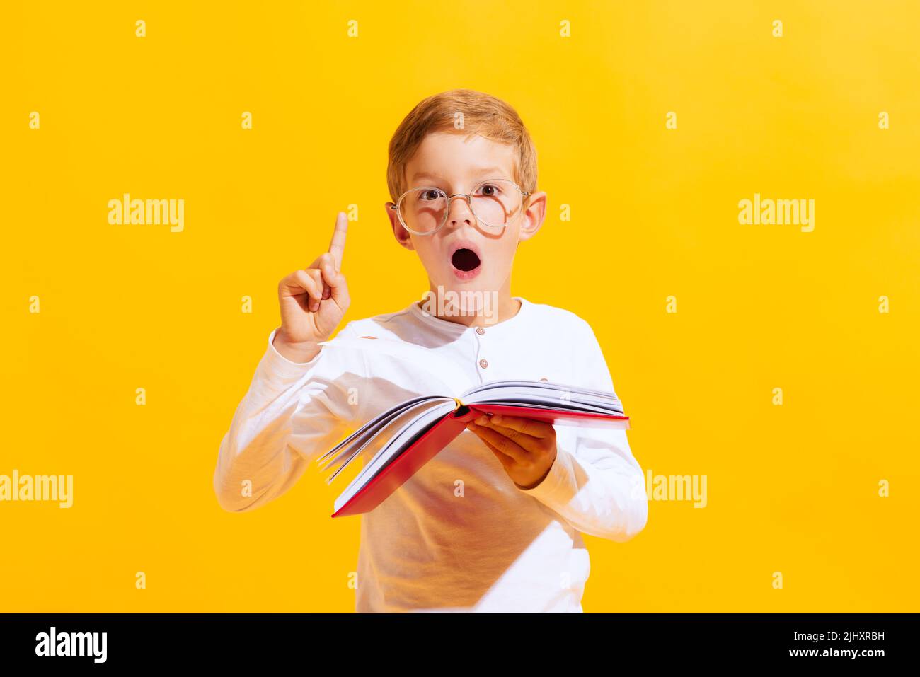 Portrait of cute little boy, happy kid reading book isolated on bright ...
