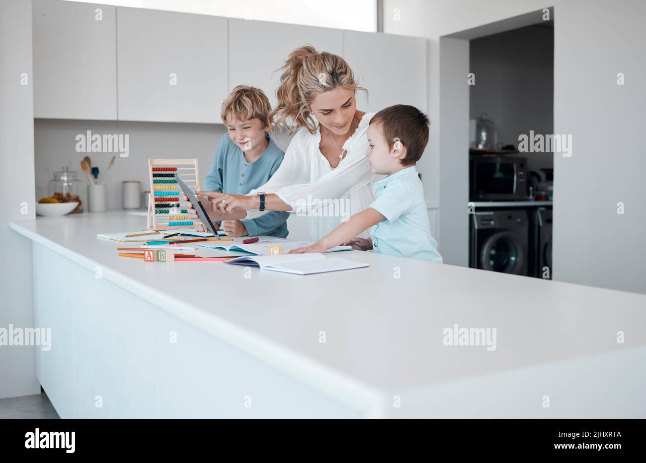 Single mother teaching little sons during homeschool class at home ...