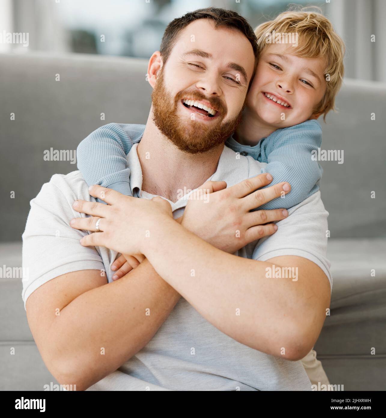 Cute little smiling caucasian boy hugging dad from behind at home ...