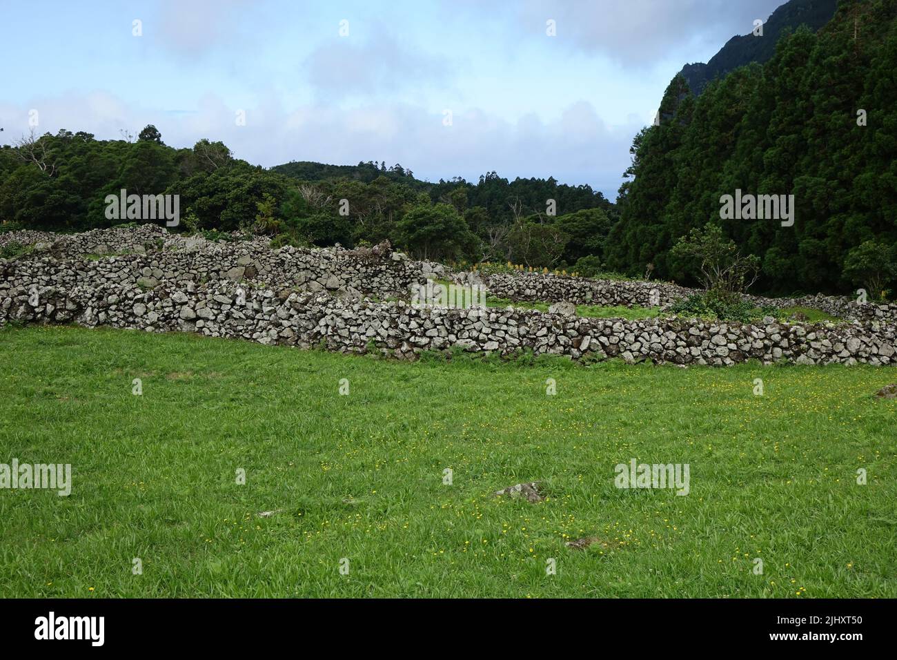 An aerial view of greenery field surrounded by rocks in background lush ...