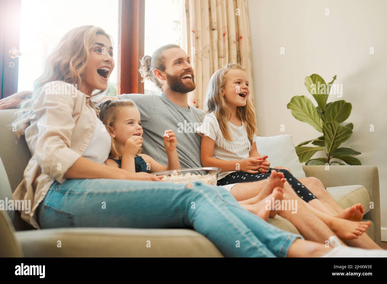 Young carefree caucasian family sitting on the couch and watching a ...