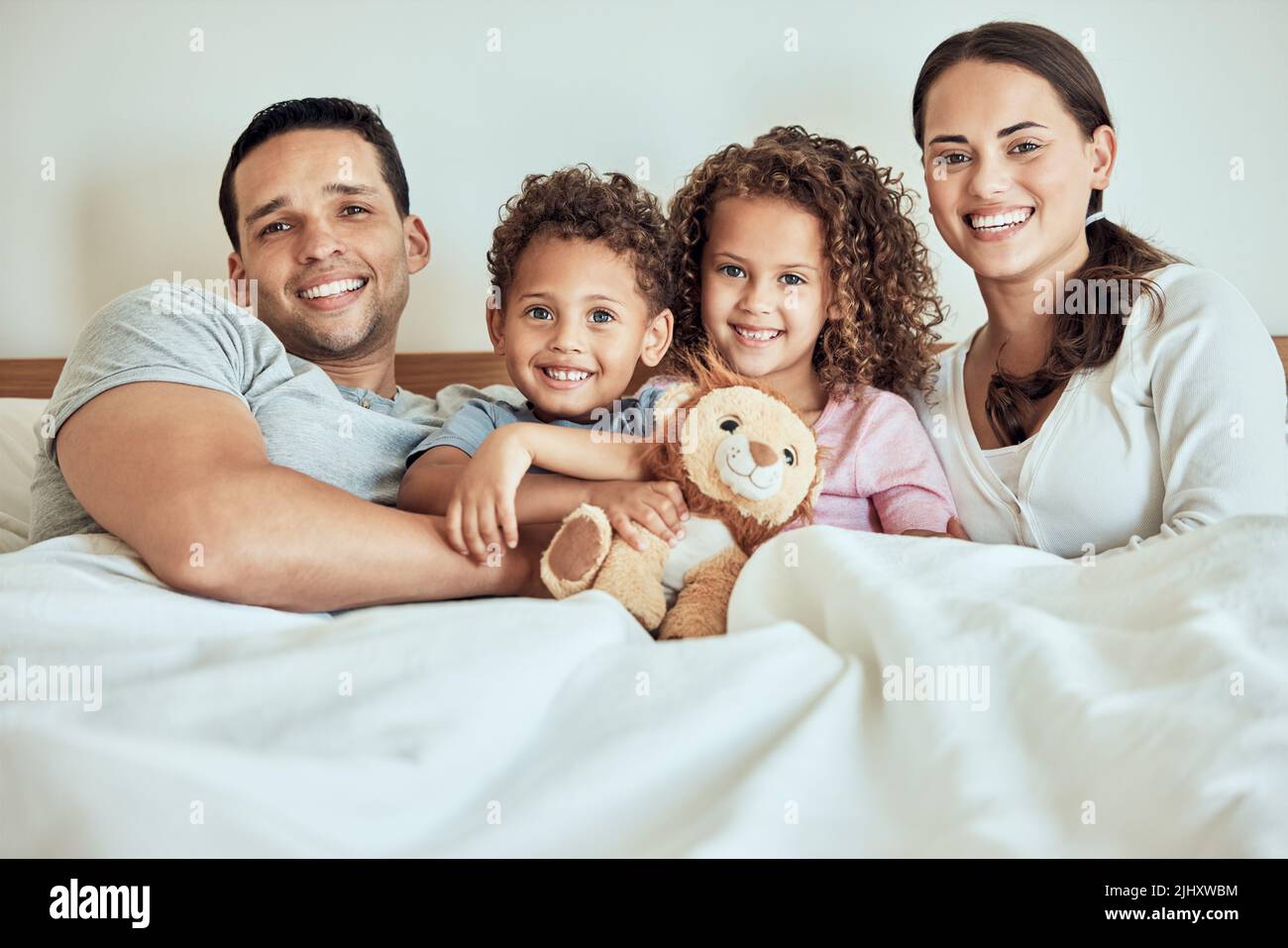 Portrait of a happy family in bed. Smiling hispanic family resting in ...