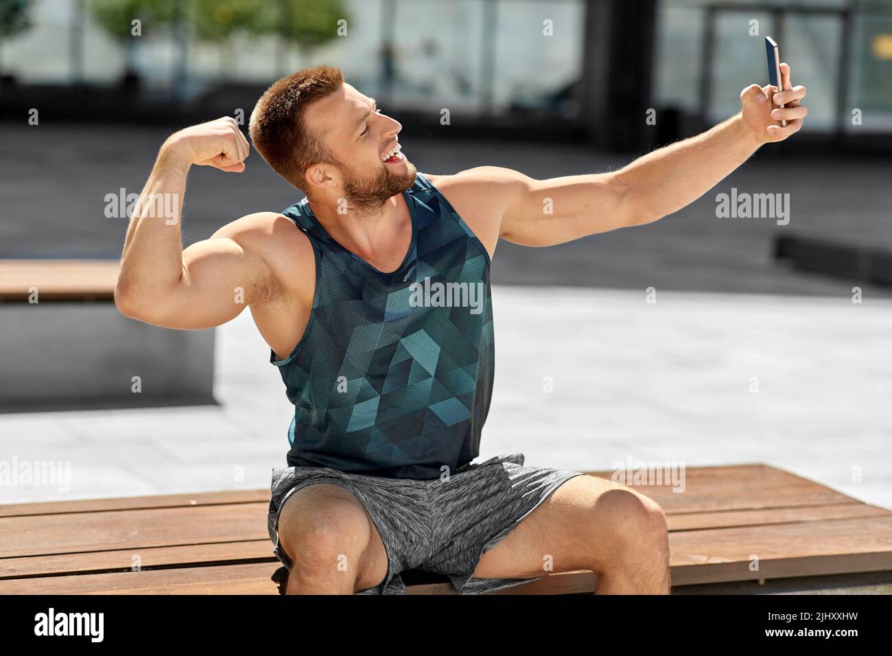 man taking selfie with phone and showing bicep Stock Photo - Alamy