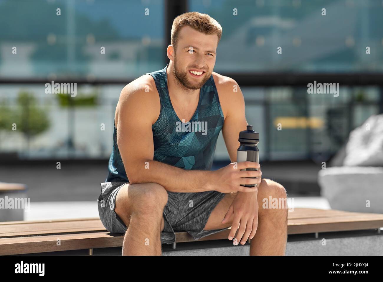 happy sportsman with bottle sitting on city bench Stock Photo - Alamy