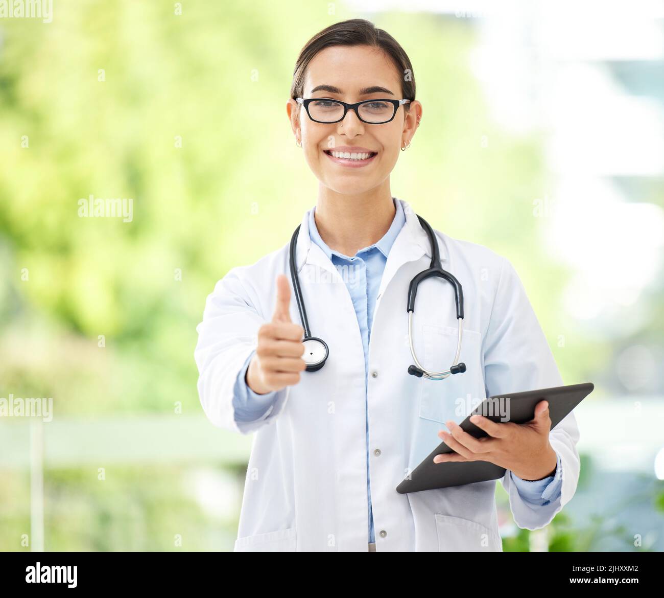 Young female Hispanic doctor wearing a labcoat and smiling while using ...