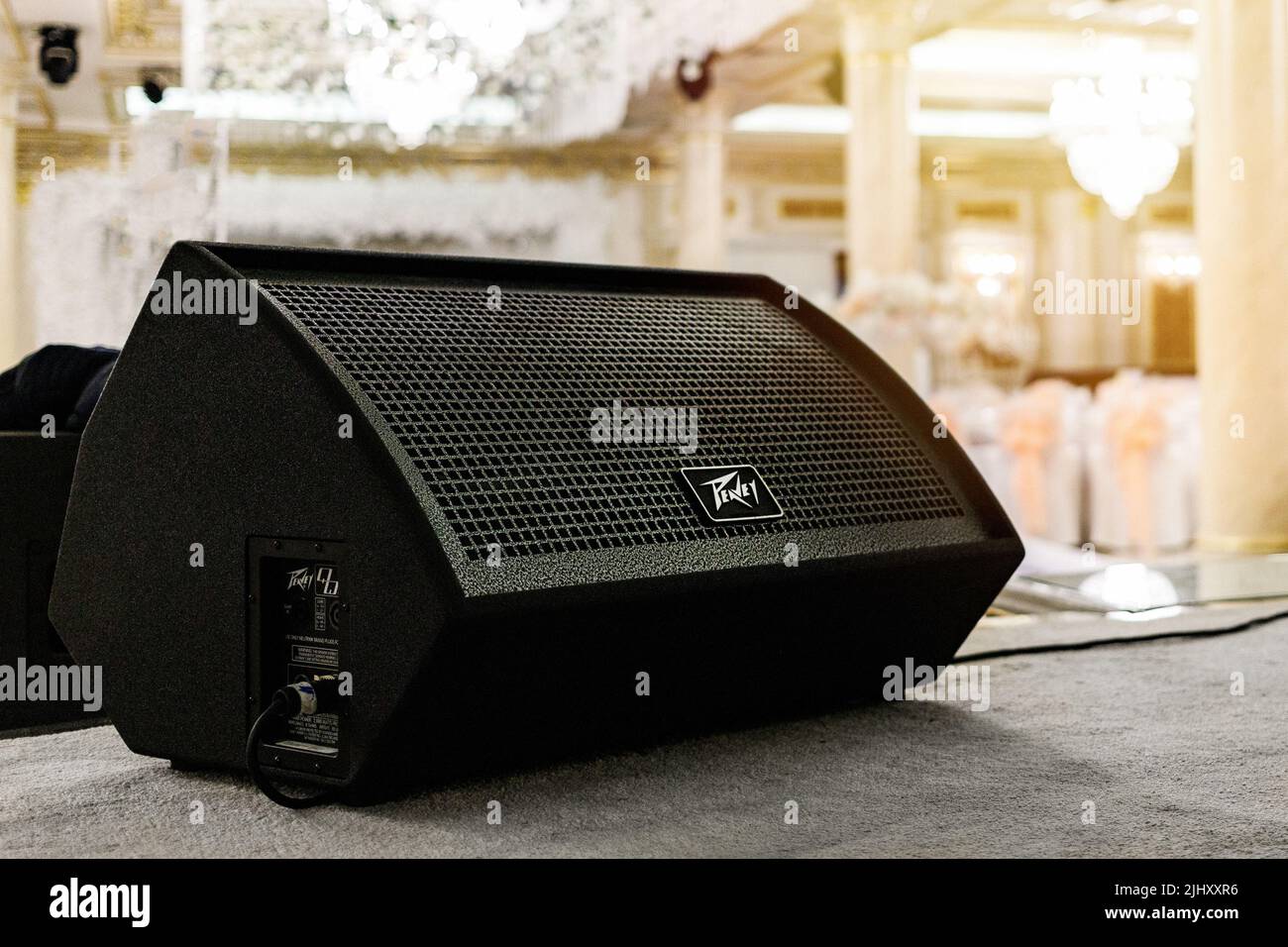 A floor-standing peavey sound monitor stands on the stage in the event ...