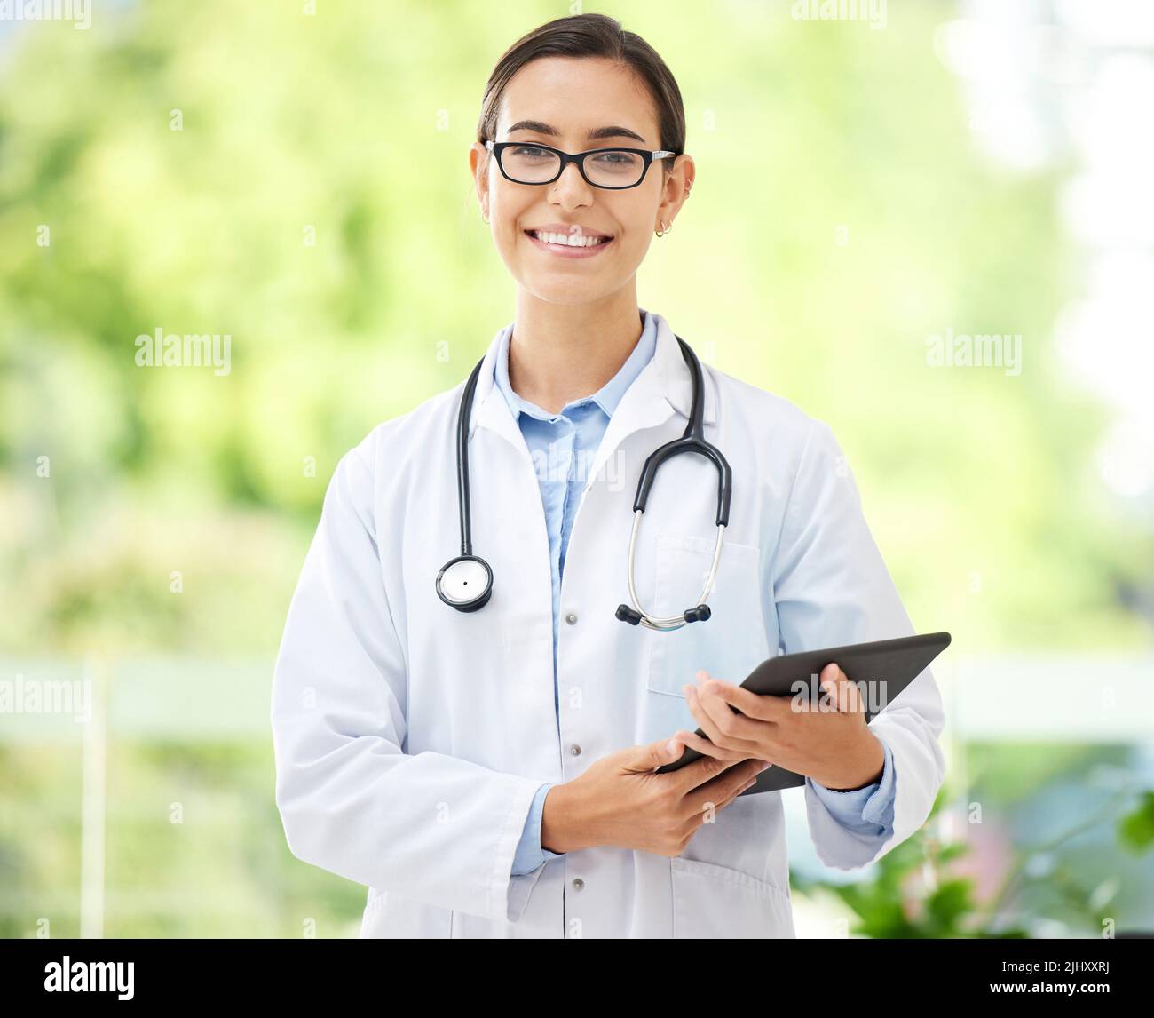 Young female Hispanic doctor wearing a labcoat and smiling while using ...