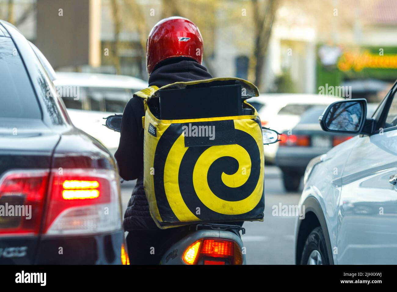 Food delivery man Yandex food with a yellow backpack in a helmet on a ...