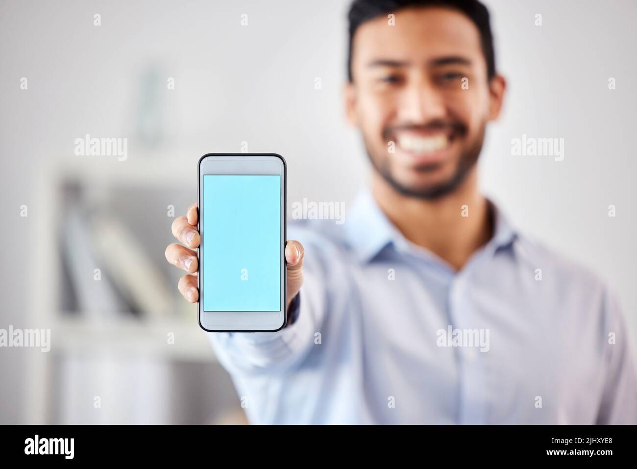 Businessman showing a blank blue screen with copyspace on his cellphone ...